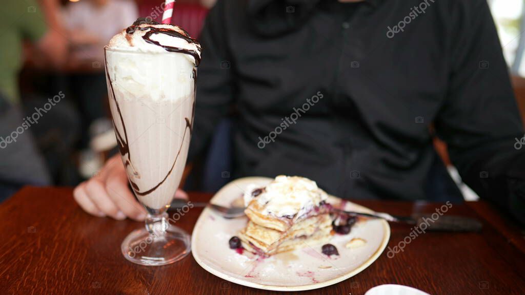 Hombre disfrutando de panqueques y batido, saboreando postre azucarado ...