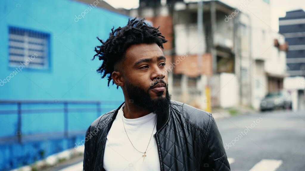 Un joven contemplativo negro caminando por la calle sintiéndose ...