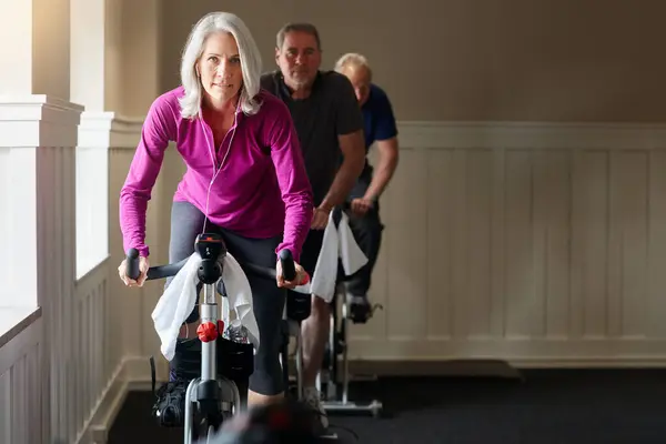 Spinning class, portrait or senior woman on bike machine in workout or ...