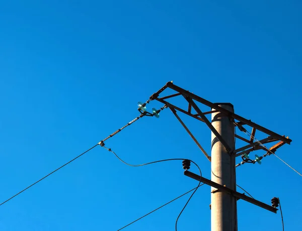 Poste eléctrico con un alambre lineal contra el cielo azul de cerca ...