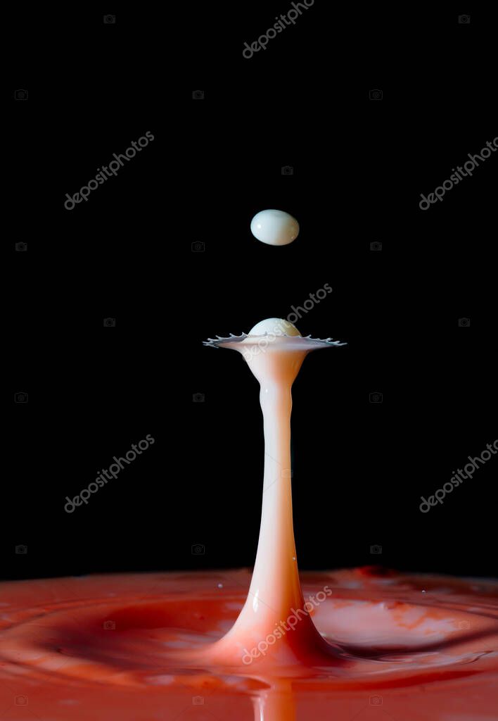 image of collision of drops of milk falling on a background of water ...