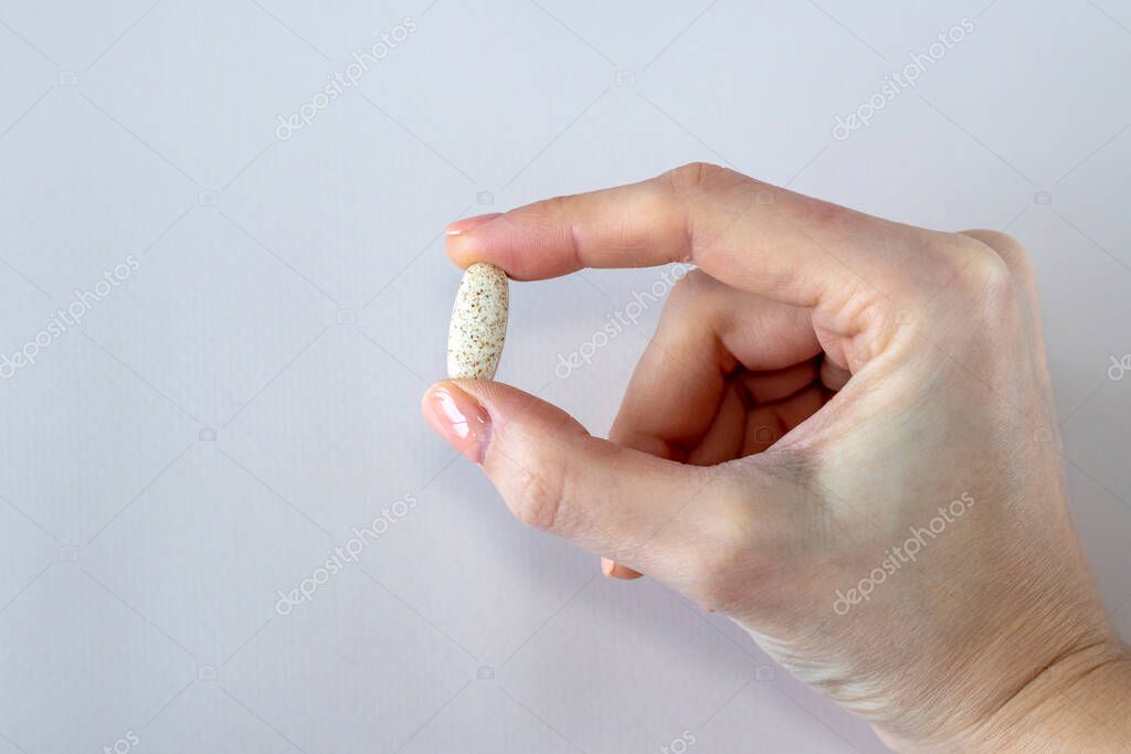 Large beige tablet with speckles in a womans hand on a beige background ...
