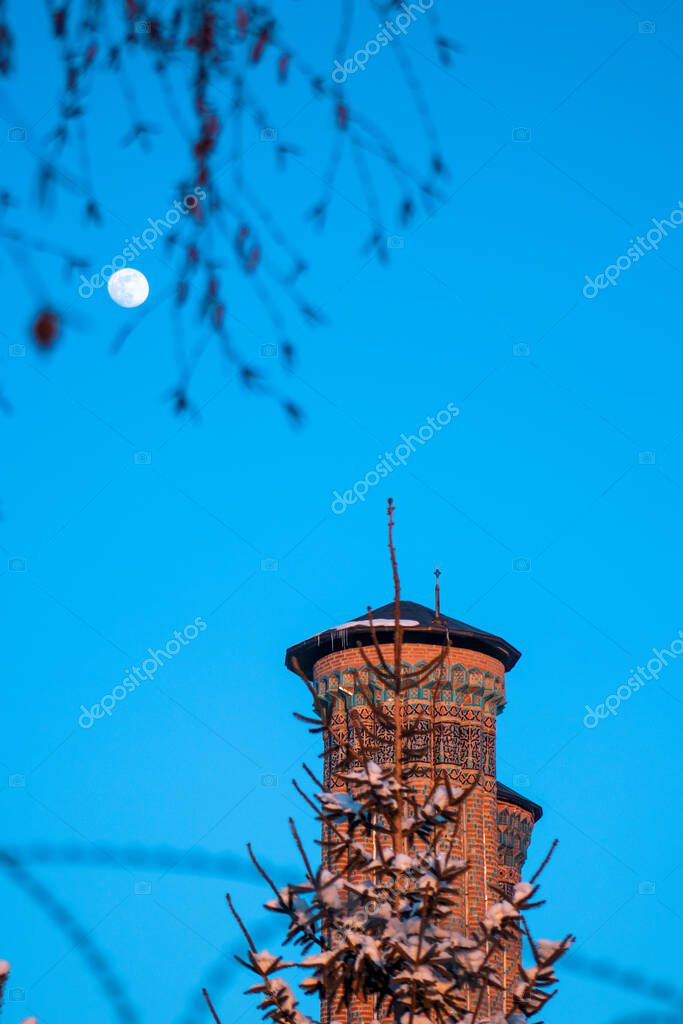 Un minarete de ladrillo con luna llena en el cielo.Doble Minarete ...