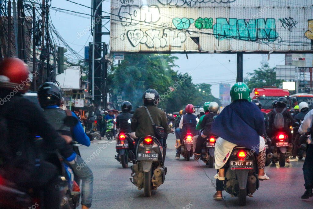 Jakarta, Indonesia in November 2022. Back view of a motorcyclist driving on a busy street on the ...