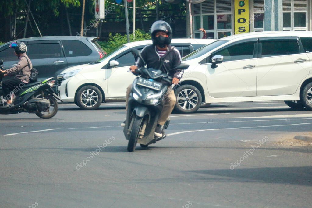 Jakarta, Indonesia in November 2022. Front view of a motorcyclist driving on a busy street on ...