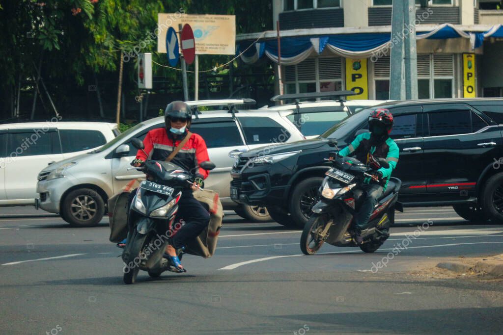 Jakarta, Indonesia in November 2022. Front view of a motorcyclist driving on a busy street on ...
