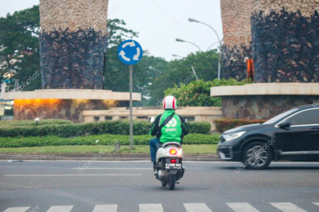Jakarta, Indonesia in November 2022. Back view of a motorcyclist driving on a busy street on the ...