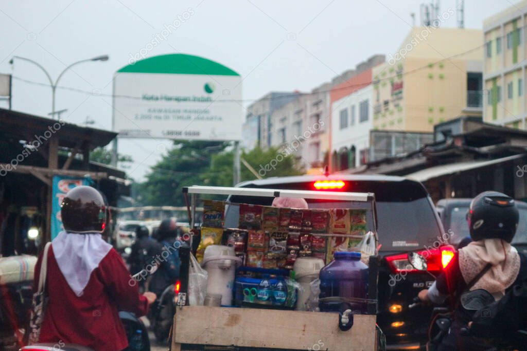 Jakarta, Indonesia in November 2022. Back view of a motorcyclist driving on a busy street on the ...