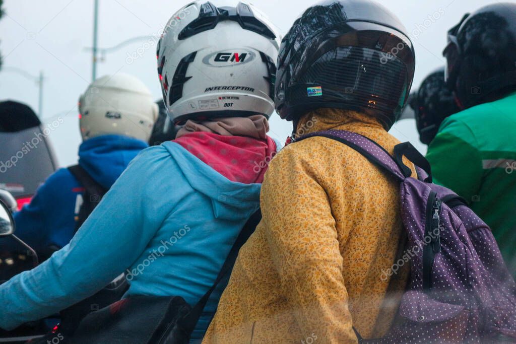 Jakarta, Indonesia in November 2022. Back view of a motorcyclist driving on a busy street on the ...