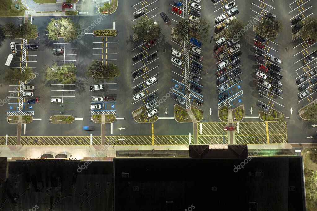 Vista aérea de un gran estacionamiento por la noche con muchos coches ...