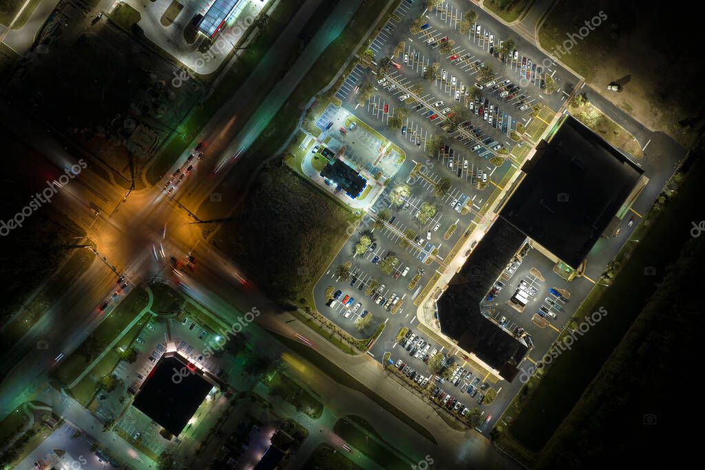 Vista aérea de un gran estacionamiento por la noche con muchos coches ...