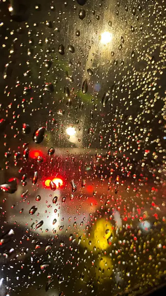 Rainy Night Drive: Red Bokeh and Droplets on Car Windshield. Defocused ...