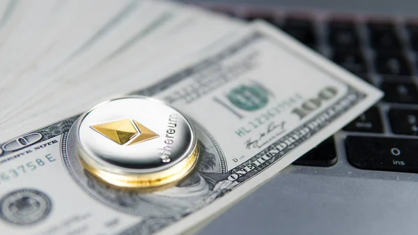 "Ethereum cryptocurrency on top of 100 dollar biils on a laptop. Profit ...