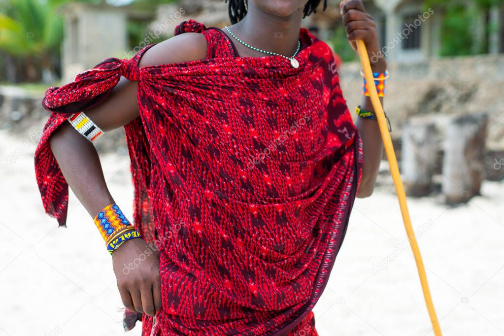 Maasai, dressed in his traditional exotic clothes, stands on a beach in ...