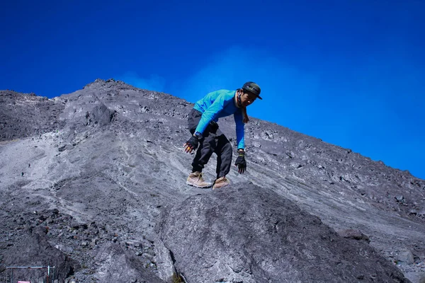 an active young male Asia on a climbing of the Mount Merapi, stan on ...