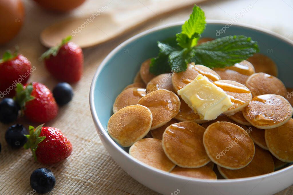 Mini panqueques con mantequilla y frutas rojas en un tazón. 2023