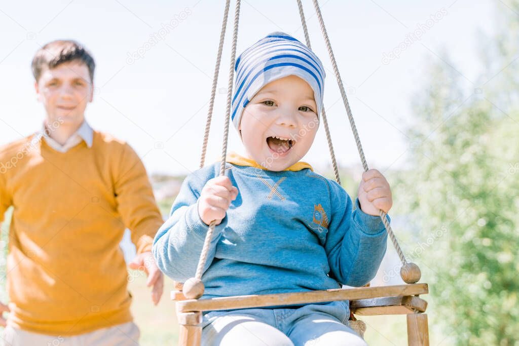 Feliz niño de tres años vestido con ropa azul amarilla columpios ...