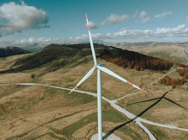 Striking wind turbine dominates the landscape, its blades casting long ...