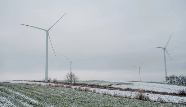 Landscape of a wind farm in a snowy field - the first snow in a rural ...