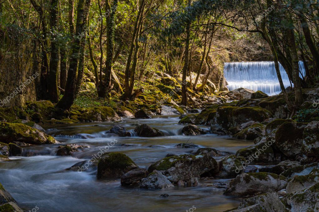 En la foto se puede ver un río sedoso corriendo entre las rocas y con ...
