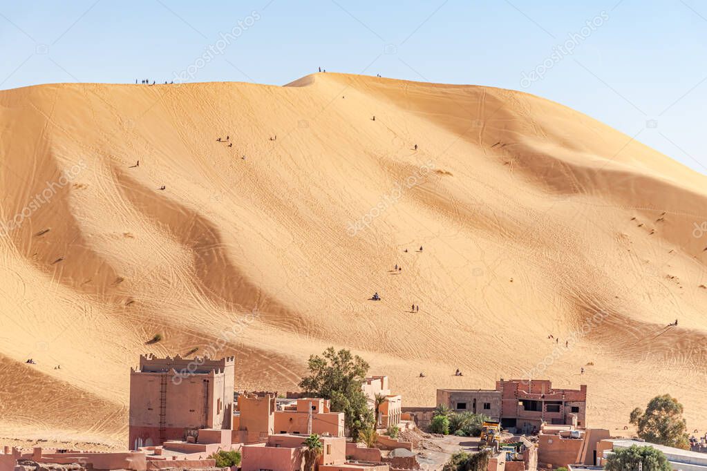 Unrecognizable tiny tourists people walking, climbing and riding quad ...
