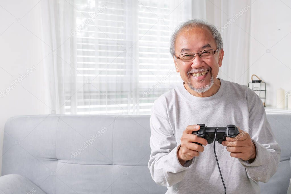 Senior using joystick, Senior holding joystick to play game, Elderly smiling, Elderly laughing ...