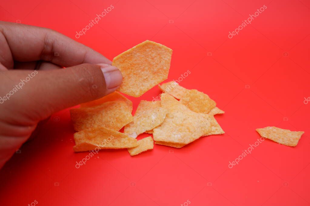 Chip de patata hexagonal de mano aislado sobre fondo rojo 2025