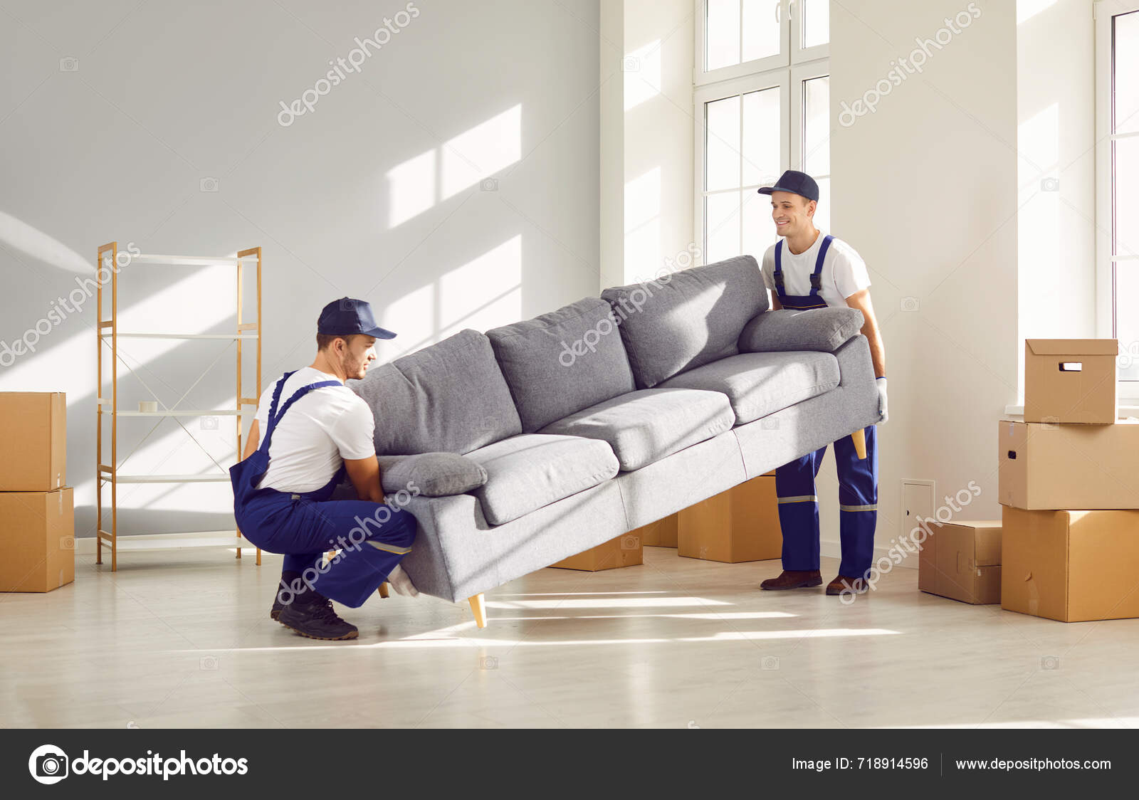 Two Young Moving Service Employees Workers Carrying Heavy Sofa Together ...
