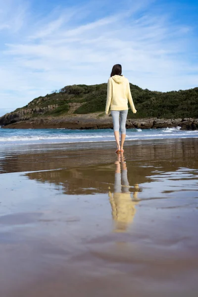 Mujer caminando descalza por la orilla del mar con su reflejo en el ...