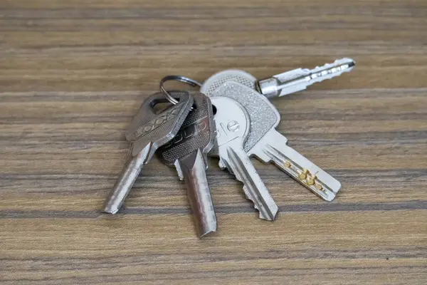 A key ring with bunch of keys on a wooden table. - Stock Image - Everypixel