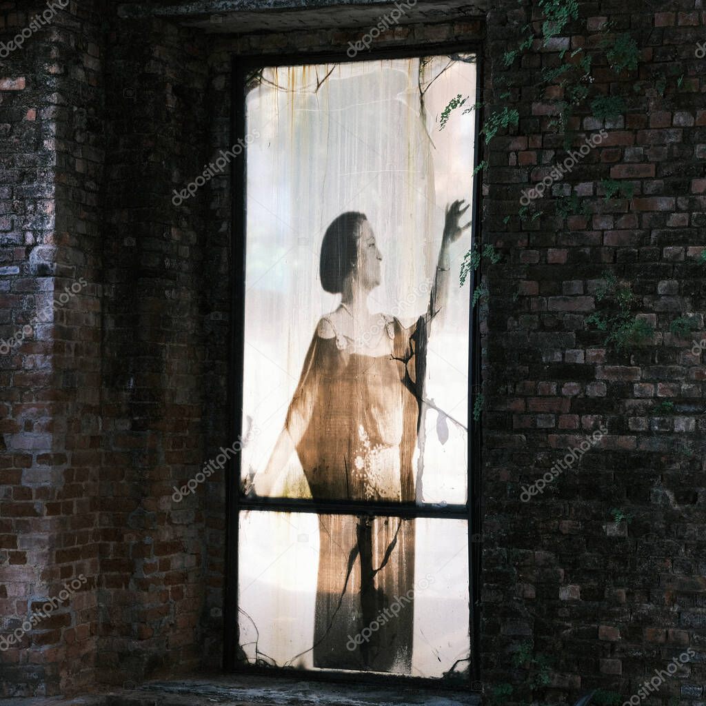 An ethereal figure of a woman is illuminated through a window, set ...