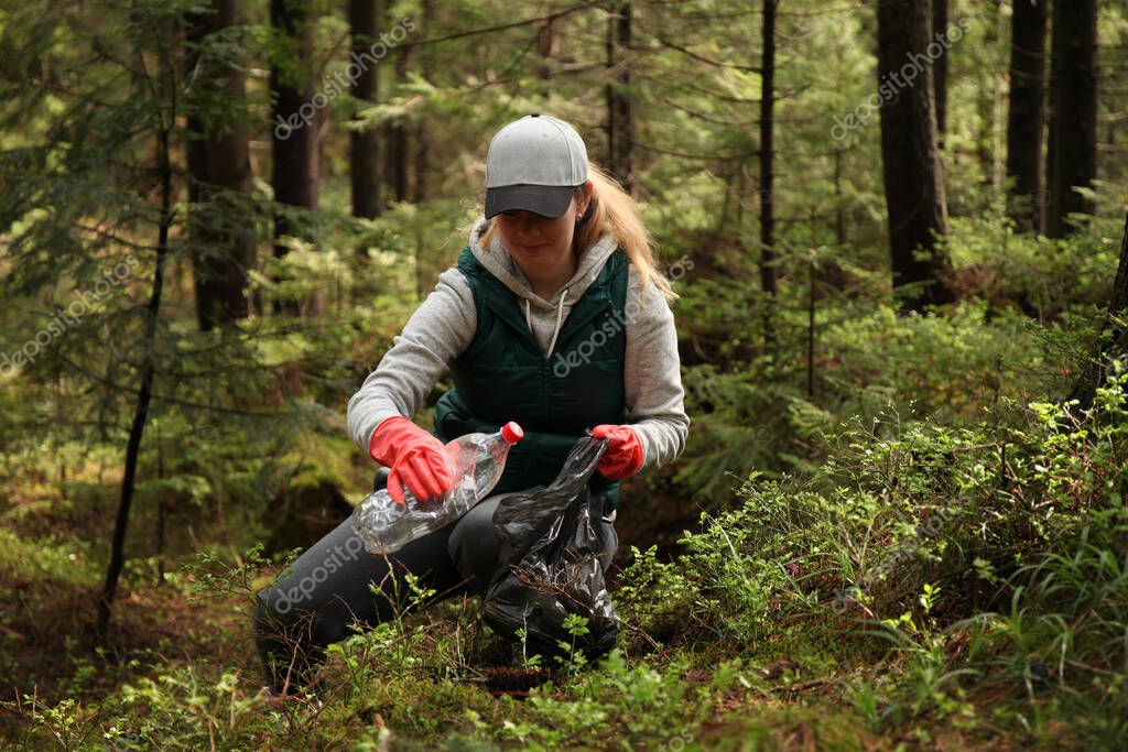 Mujer voluntaria adulta limpia basura y plástico que contamina el medio ambiente en el bosque. 2024