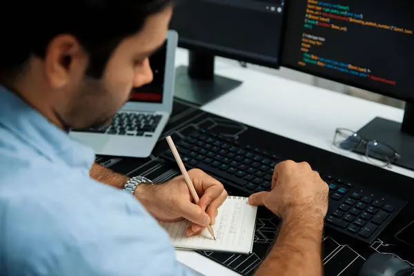 Smart IT developer writing data memos software development on papers coding on laptop and two pc ...